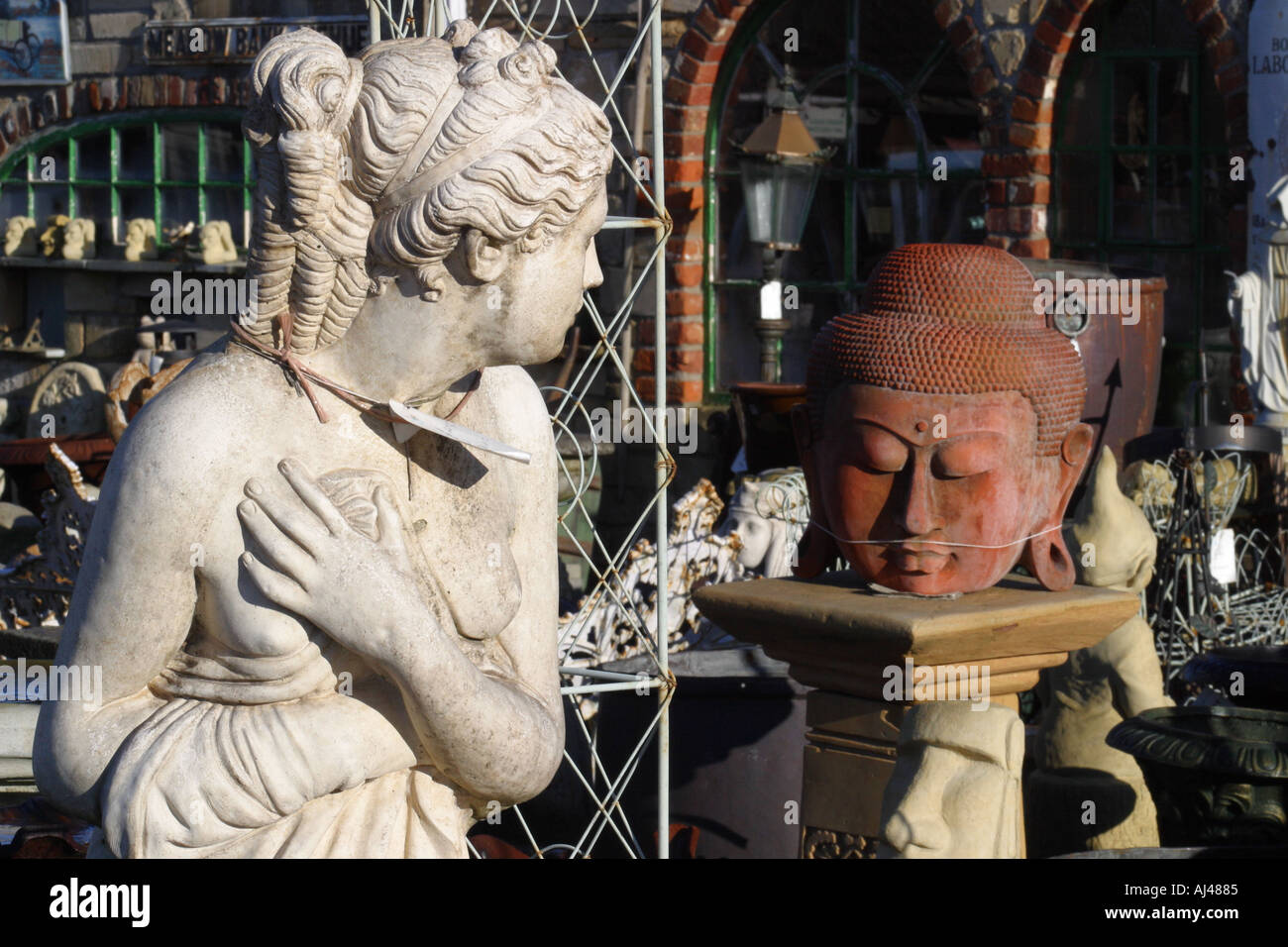 Salvage yard old statues female figure and buddha in an architectural ...