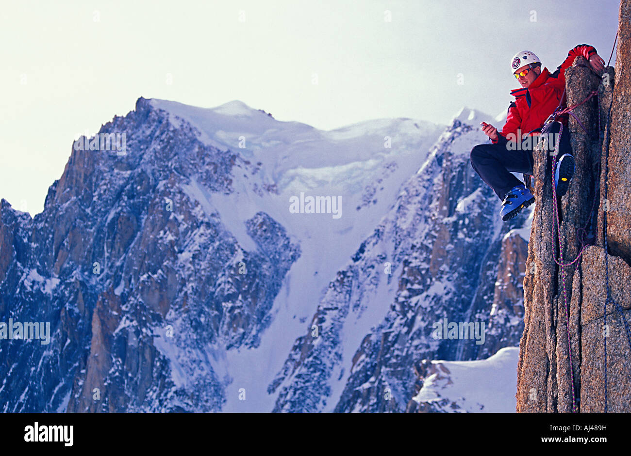 Climber roped to a rock in the French alps with a mobile phone going to ...