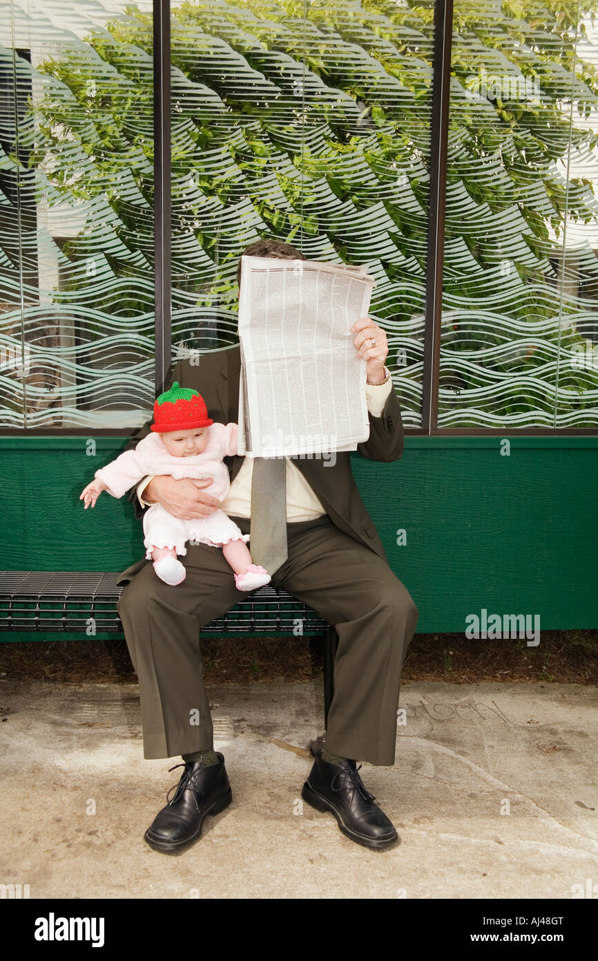 Businessman holding baby at bus stop Stock Photo - Alamy