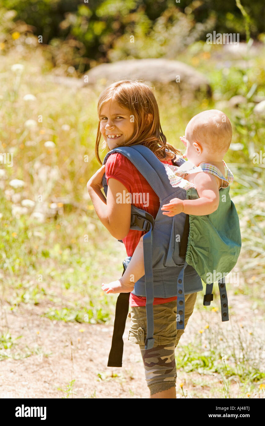 Girl carrying baby sibling on back Stock Photo - Alamy