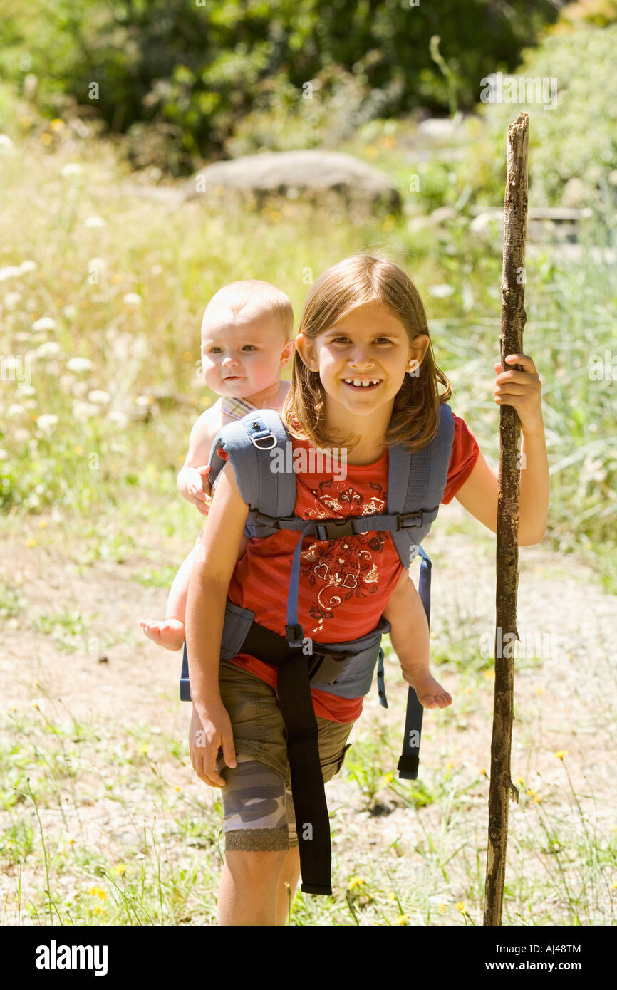 Girl carrying baby sibling on back Stock Photo - Alamy