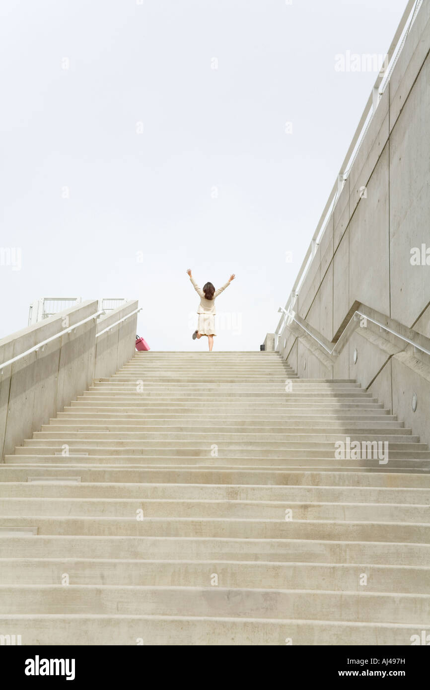 Businesswoman with arms raised at top of steps Stock Photo - Alamy