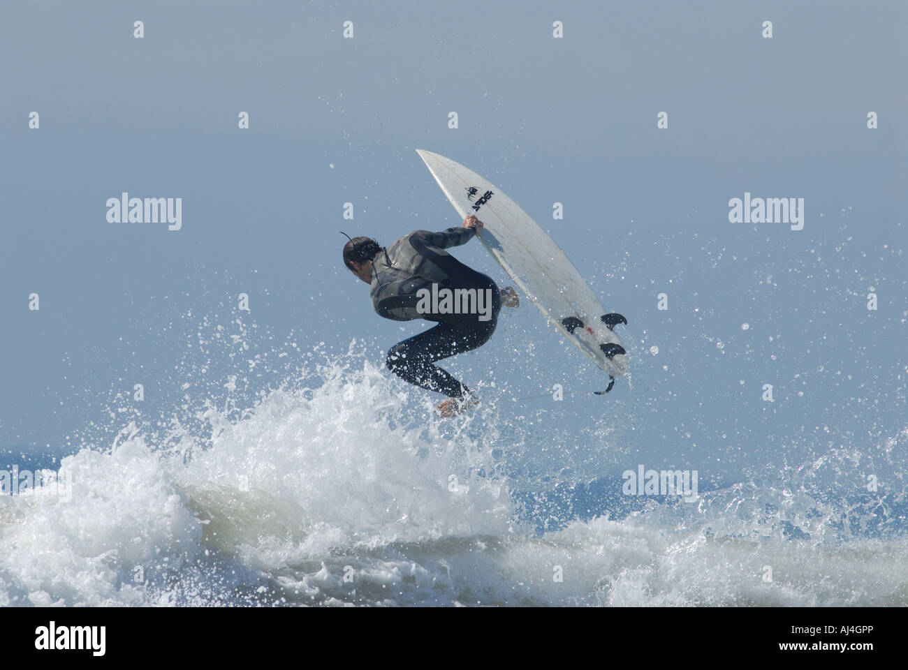 Surfer airborne holding onto surfboard Stock Photo - Alamy