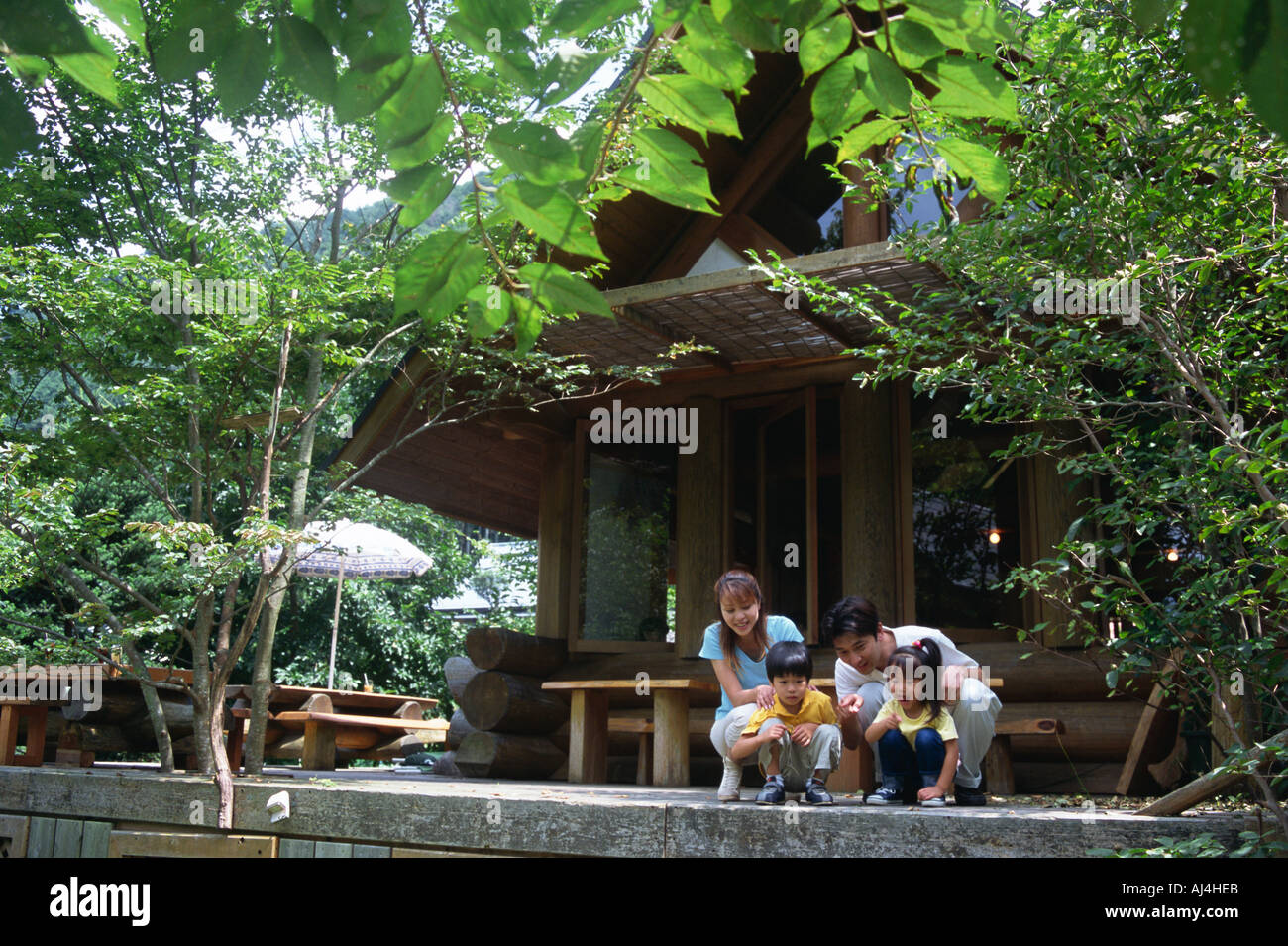 Family sitting outside of log cabin Stock Photo - Alamy