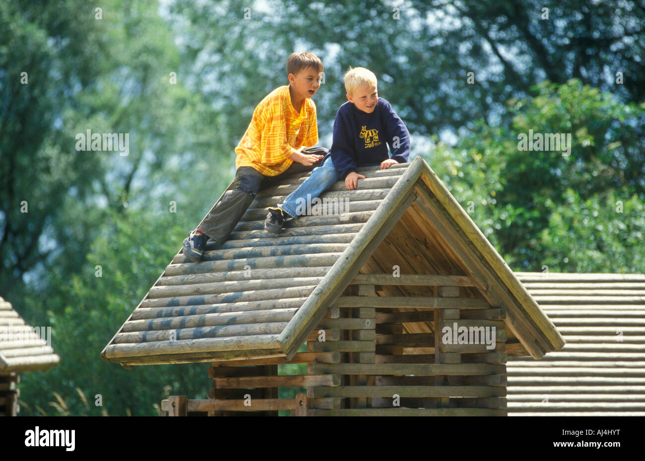 two young boys playing on top of a wooden hut on a children´s ...