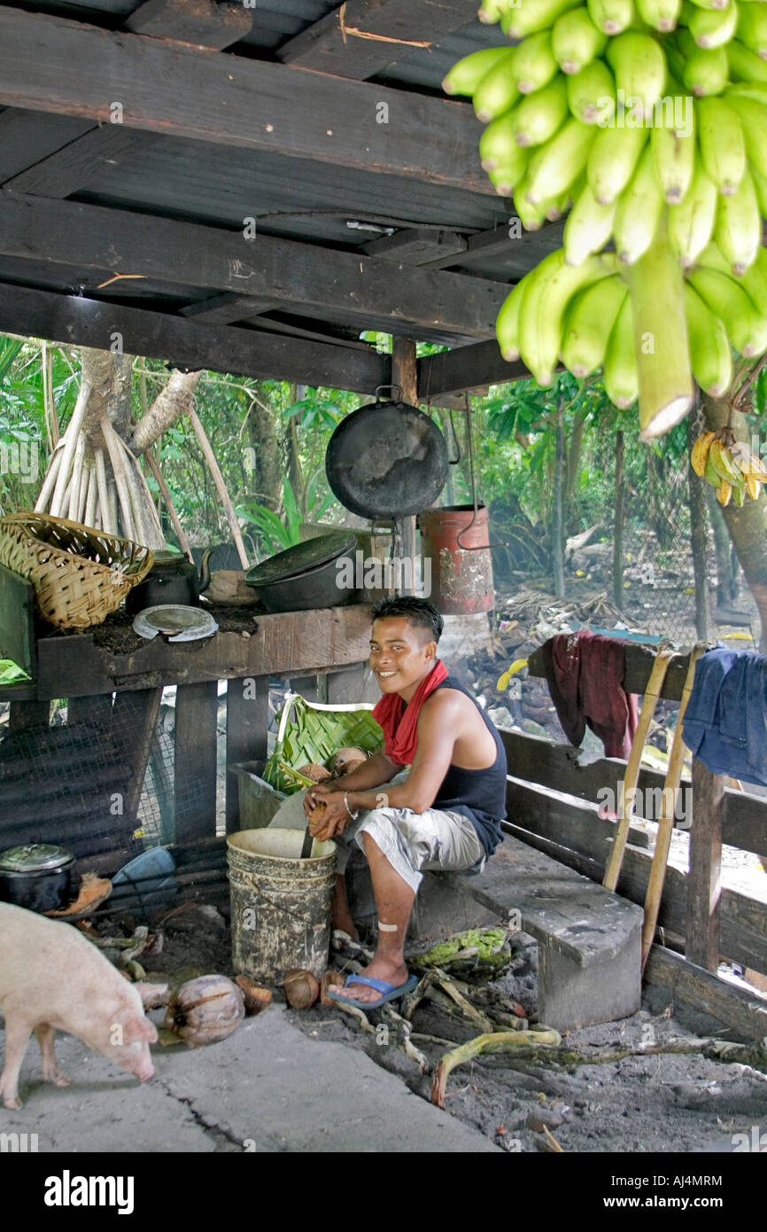Young man cooks dinner over a coconut husk fire in his kitchen Stock ...