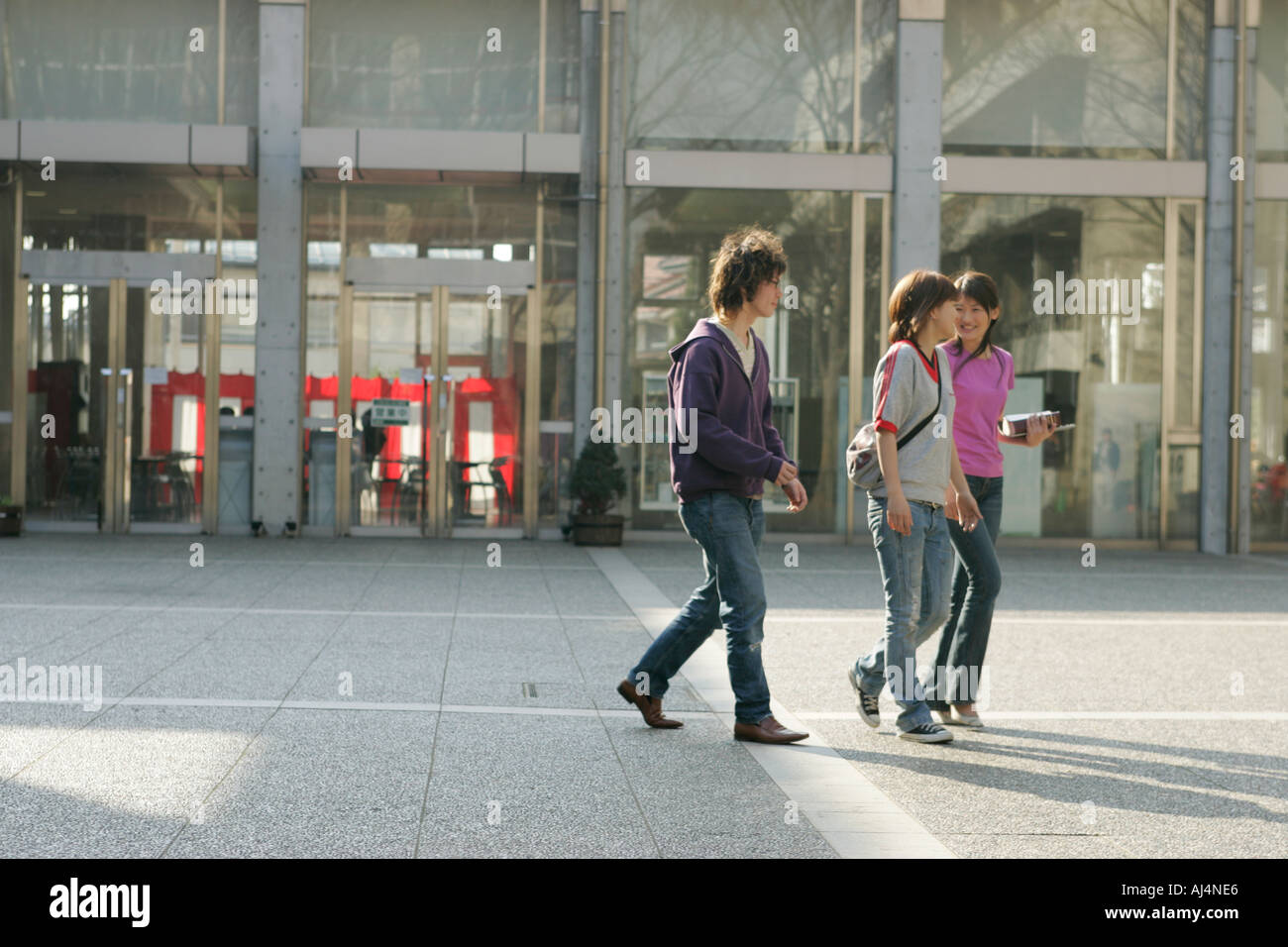Three college students walking Stock Photo - Alamy