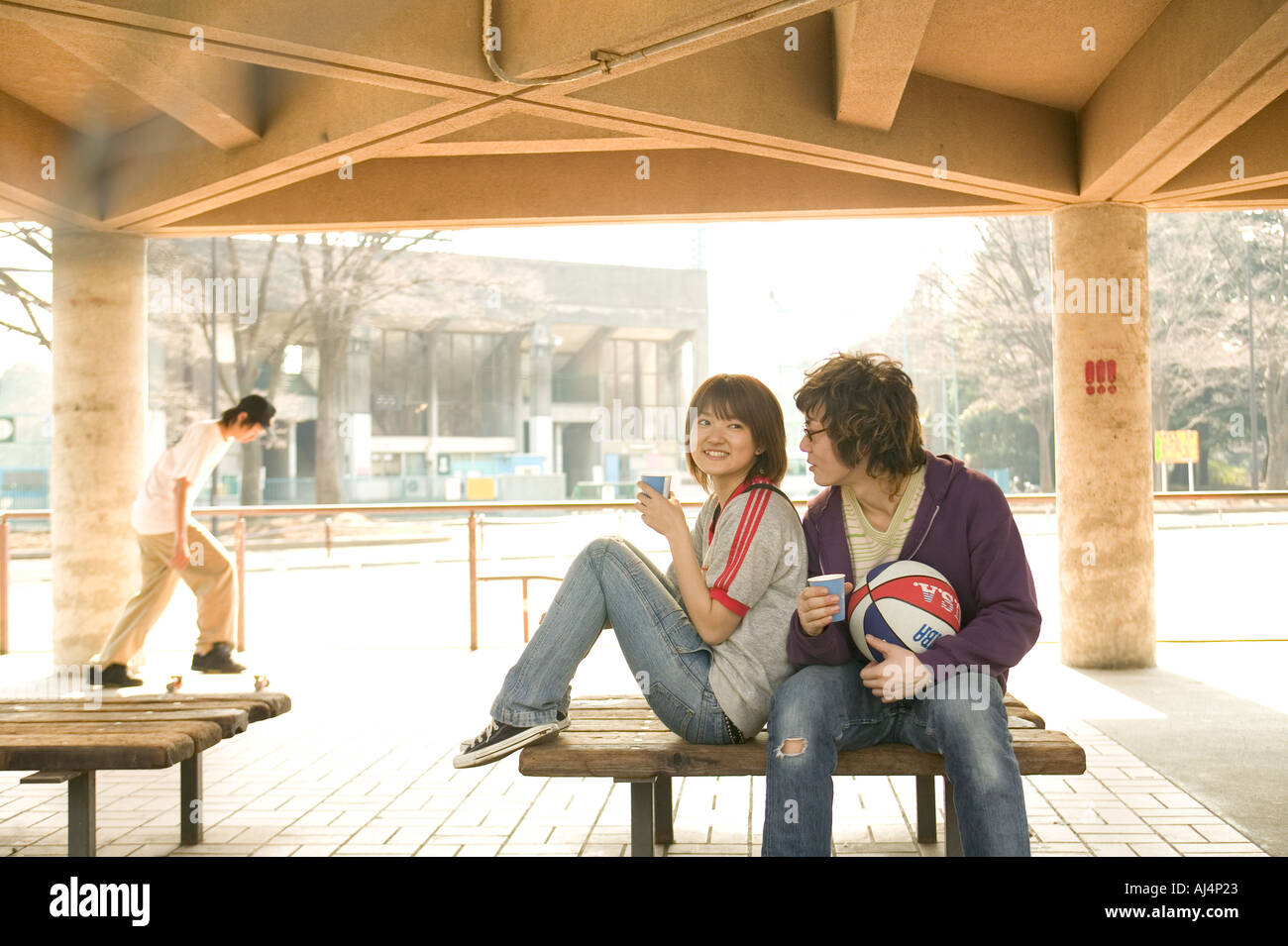 Two college students sitting on bench and talking Stock Photo - Alamy