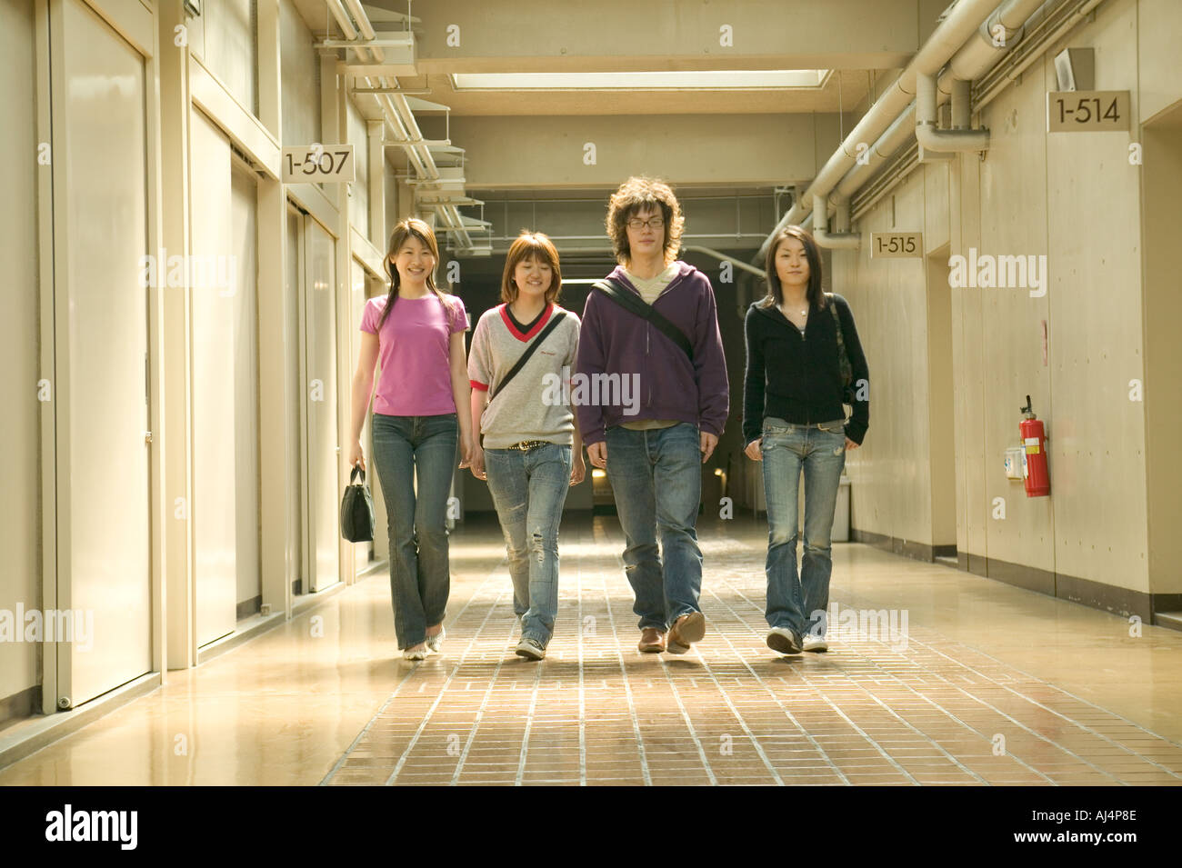 Four college students walking down corridor Stock Photo - Alamy