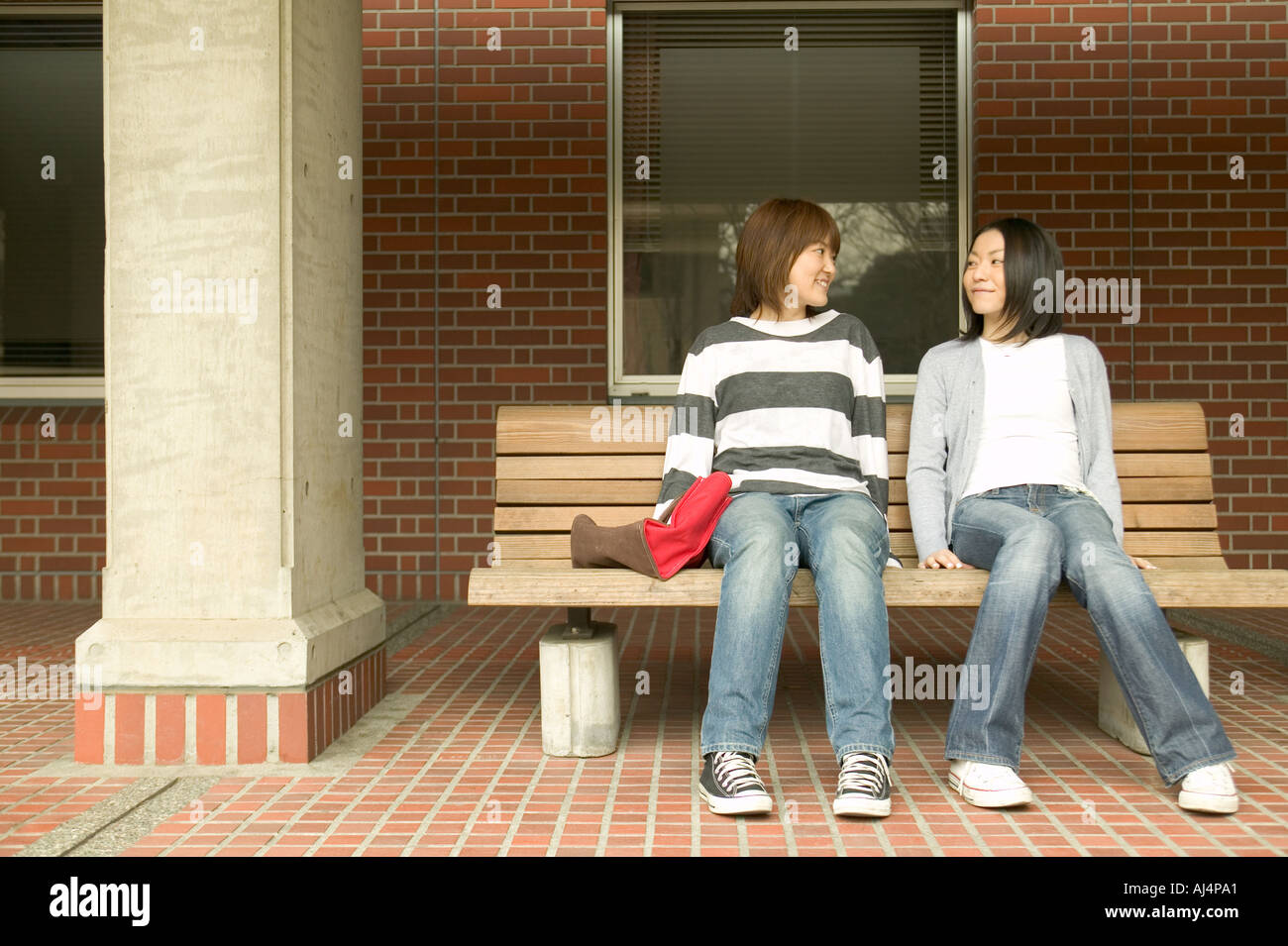 Two college students sitting on bench and talking Stock Photo - Alamy