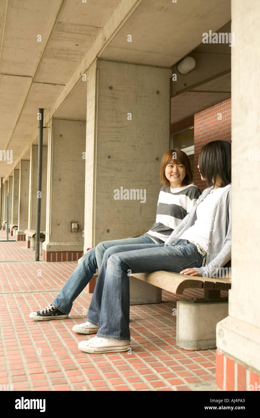 Two college students sitting on bench and talking Stock Photo - Alamy
