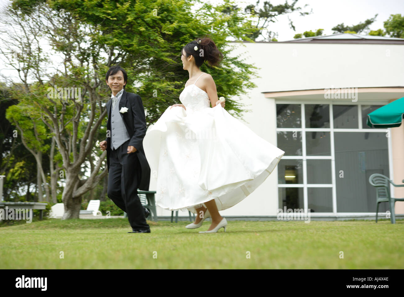 Bride and groom running on lawn Stock Photo - Alamy