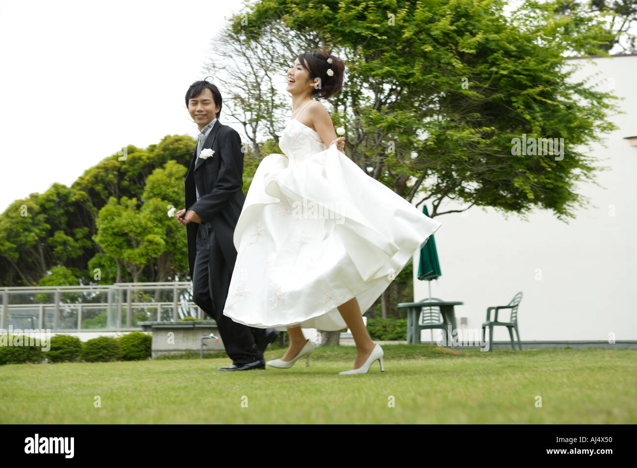 Bride and groom running on lawn Stock Photo - Alamy