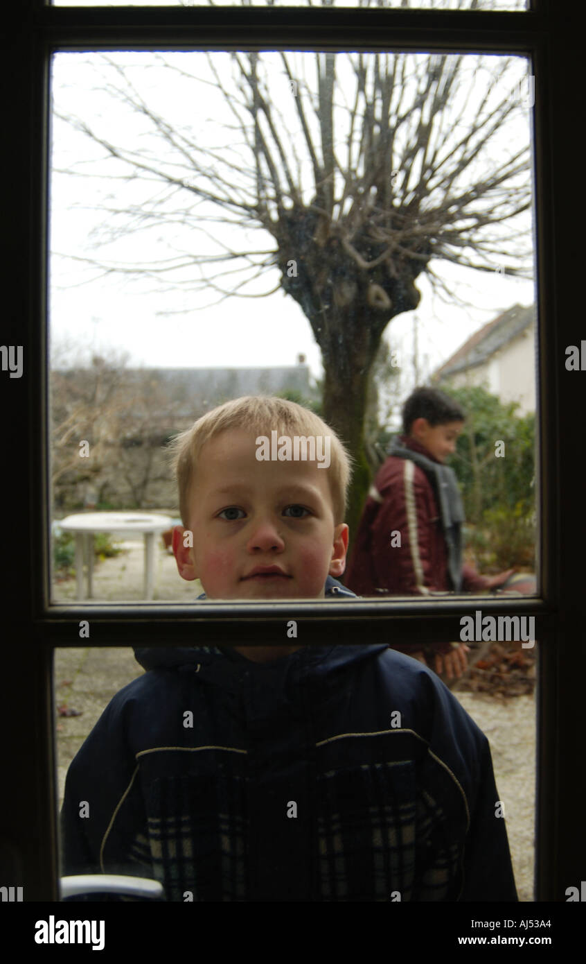 portrait of a young boy loking through window Stock Photo - Alamy