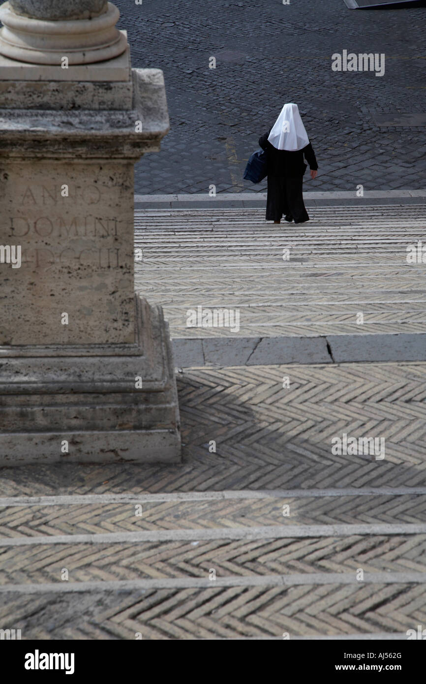 A nun in full habit walking down steep steps past column Rome Lazio ...