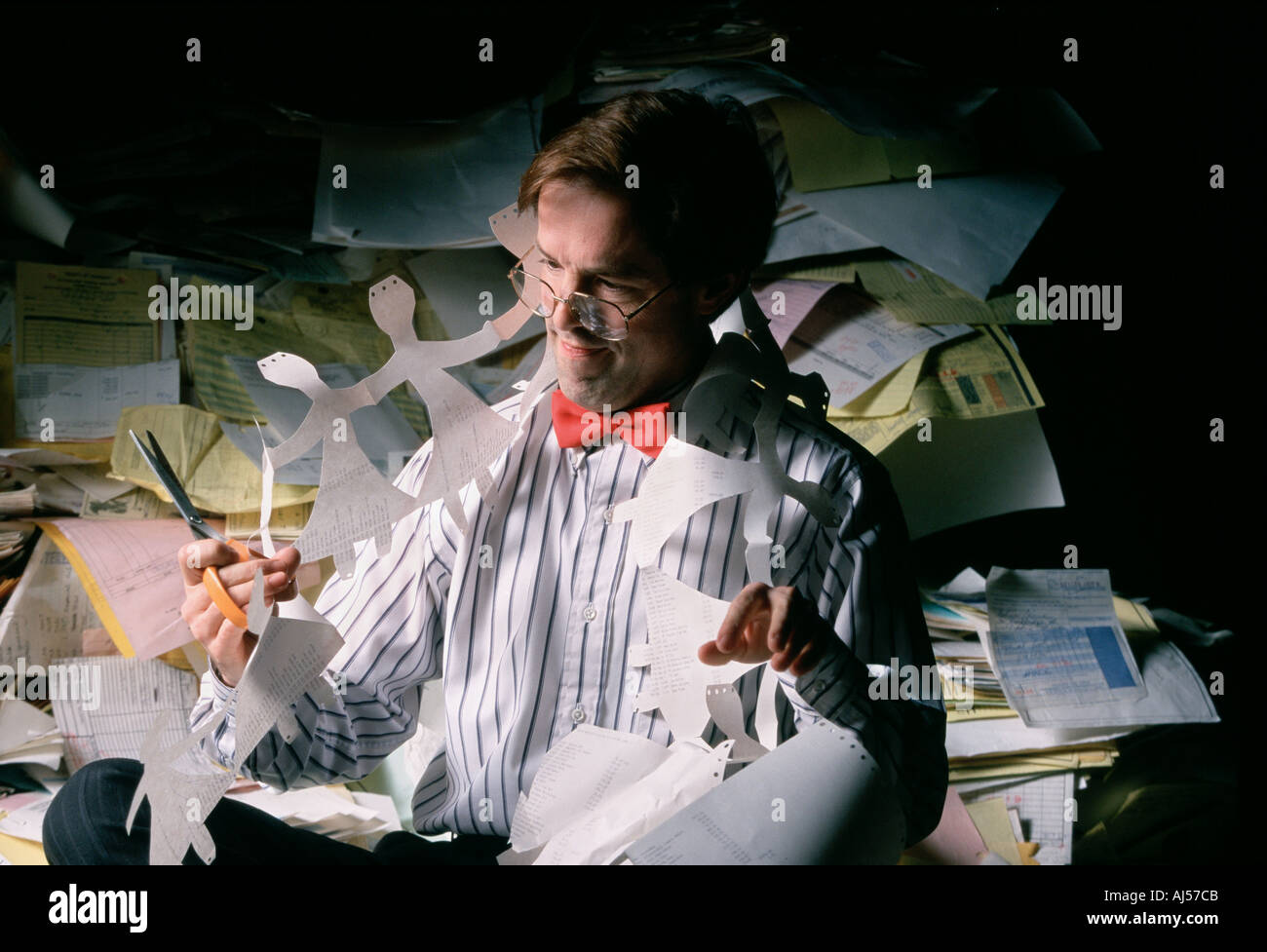 Stressed executive cutting up a huge pile of invoices and paperwork ...