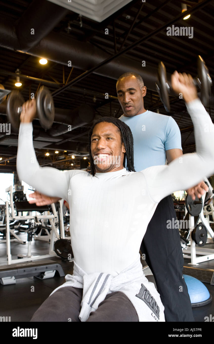 two 2 fit fitness males men exercising in a gym shoulder workout spot ...