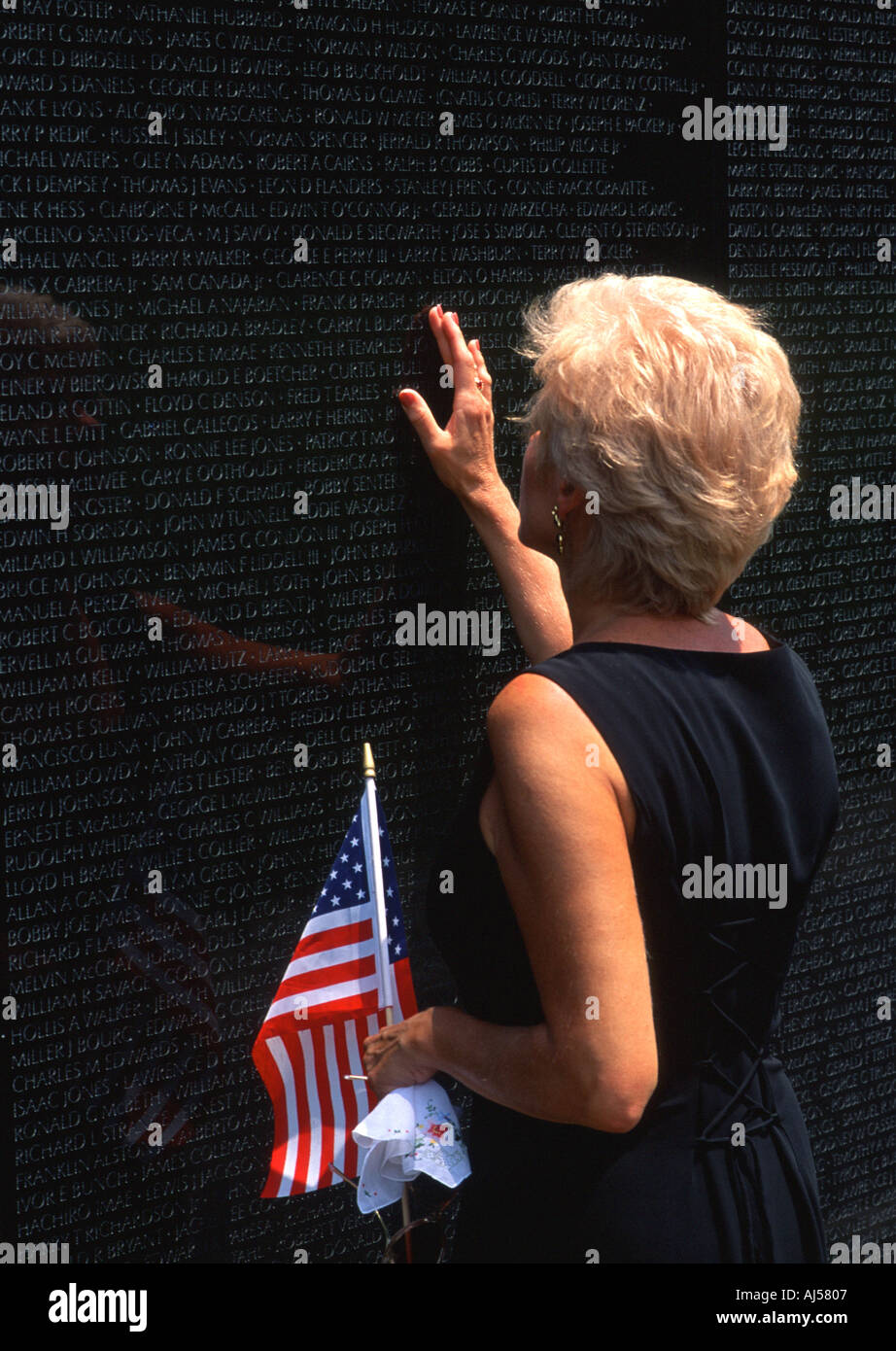 Woman touching and remembering loved one at Vietnam Memorial Washington ...