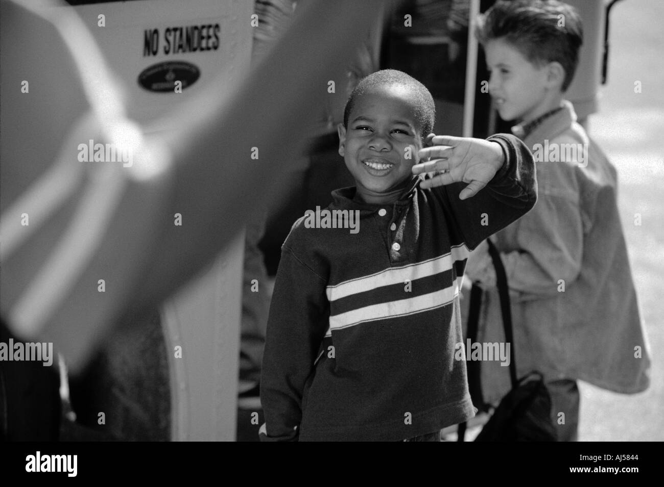 African American student saying goodbye to mother getting on school bus ...