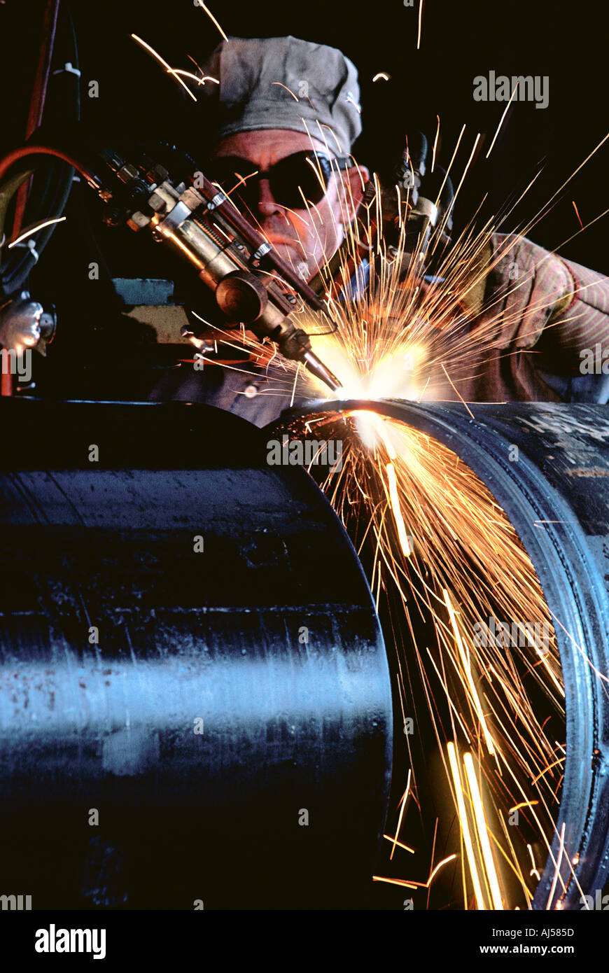 Male Caucasian pipe cutter with acetylene torch cutting oil pipeline ...