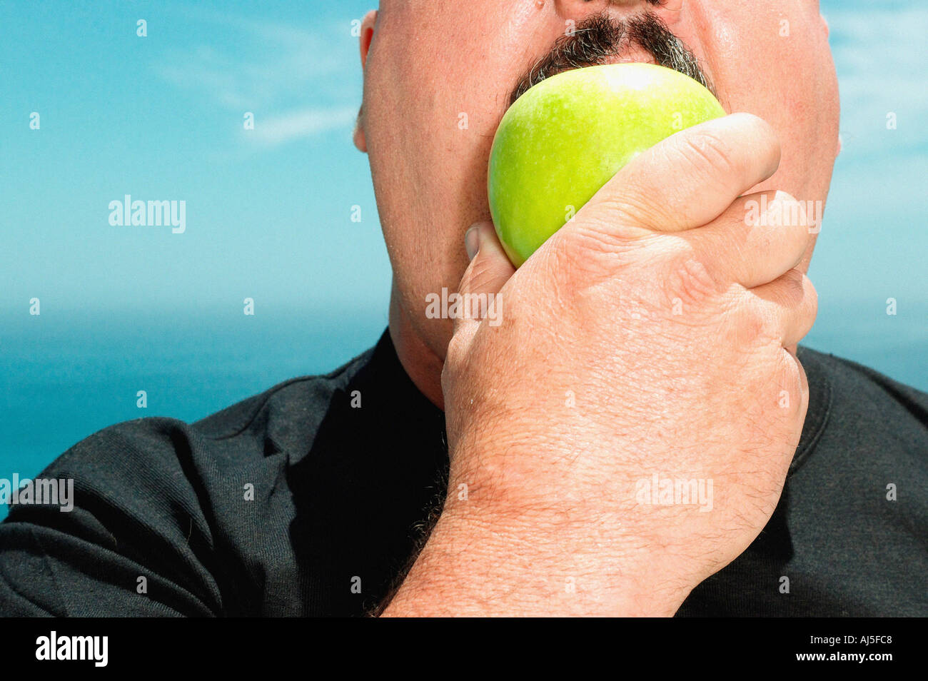 Large man eating an apple Stock Photo - Alamy