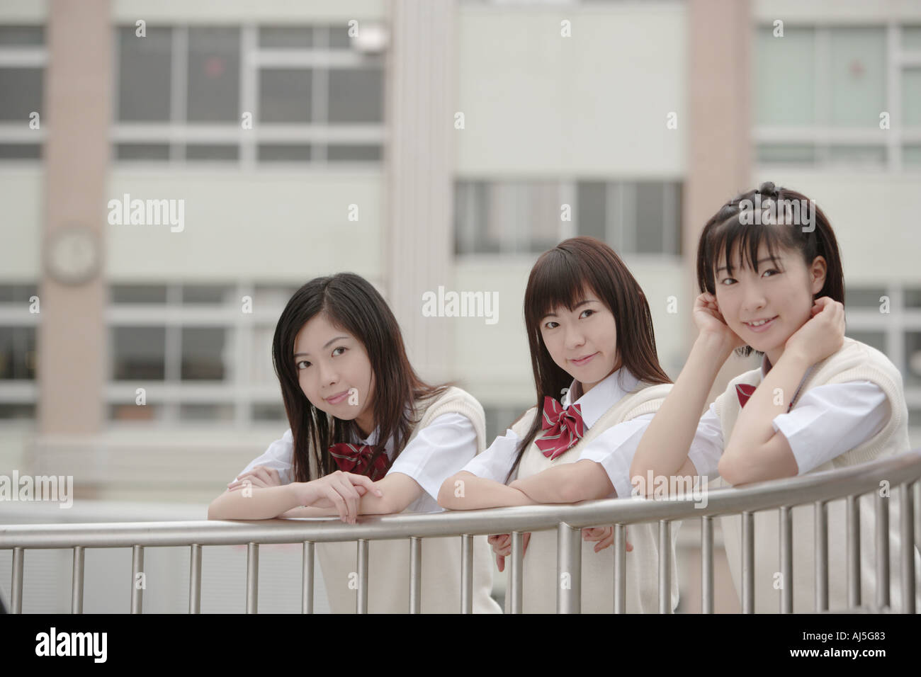 Three high school girls leaning on railing Stock Photo - Alamy