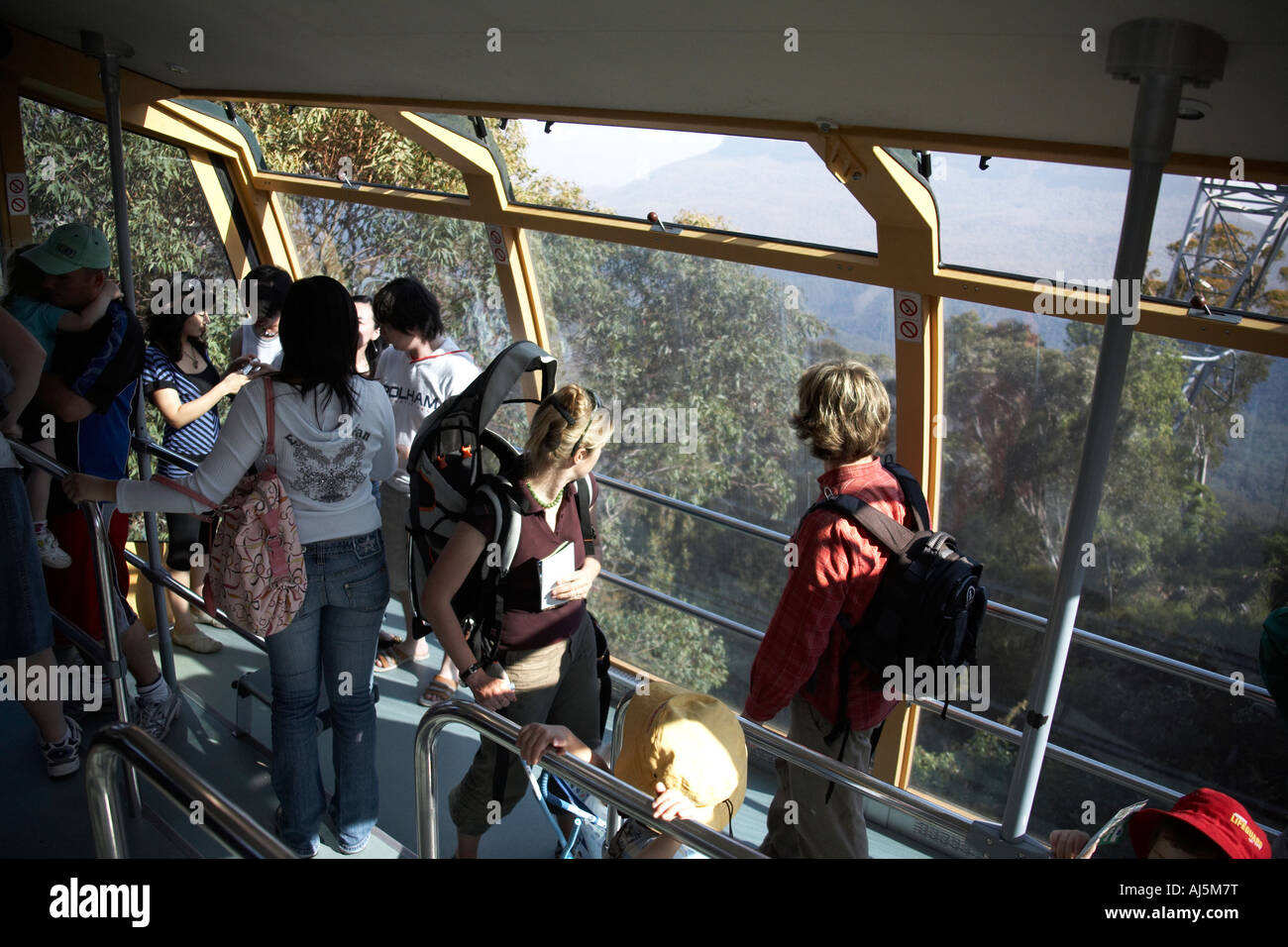 Passengers in cableway cable car descending from clifftop to forest ...