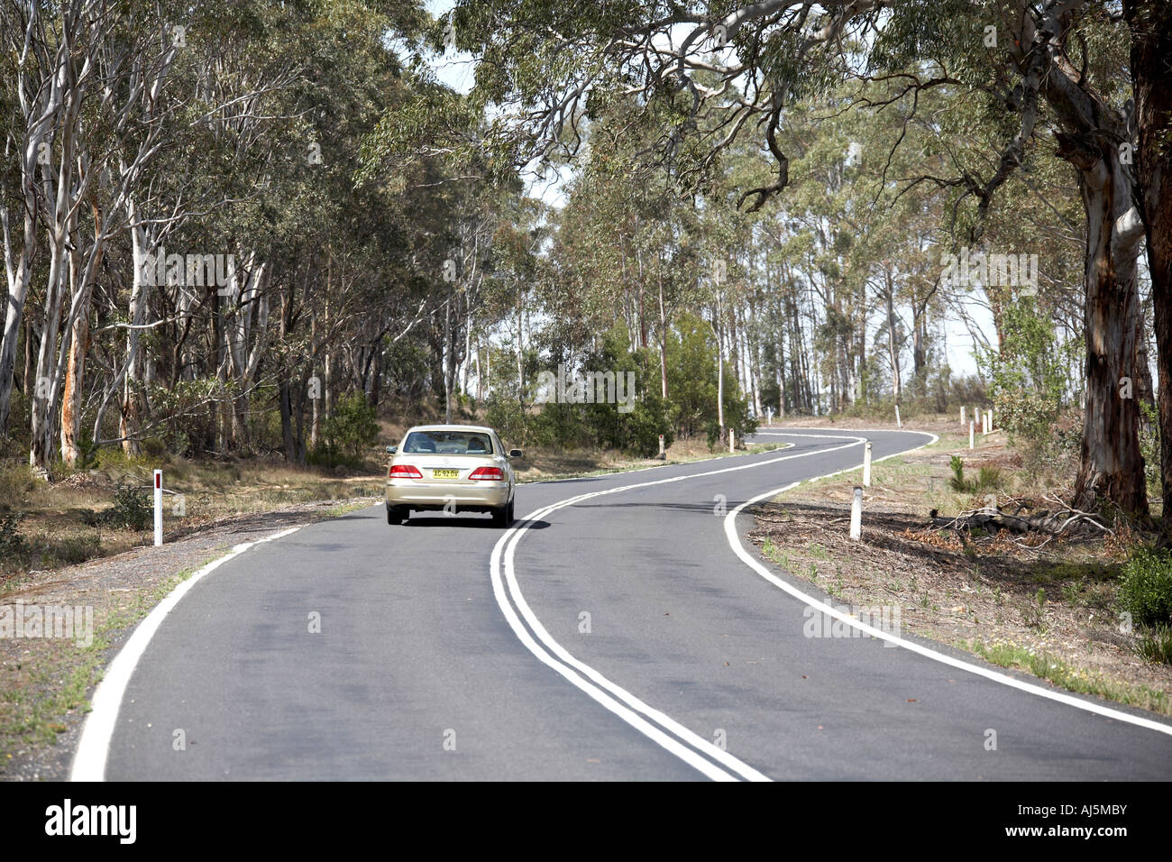 Road with bend receding into the distance and car in countryside near ...