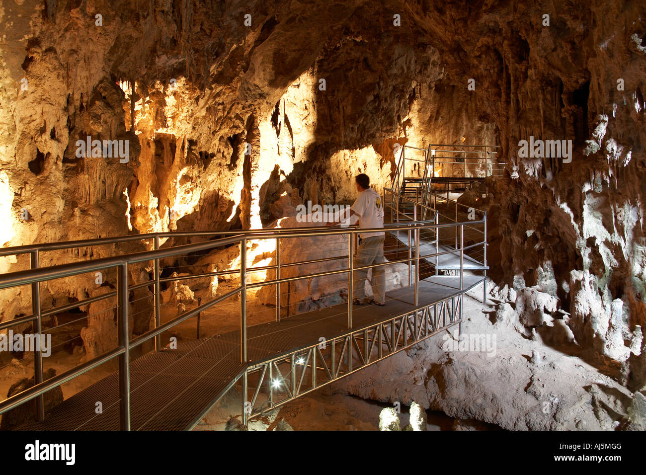 Man standing on stainless steel walkway in Nettle Cave of Jenolan Caves ...