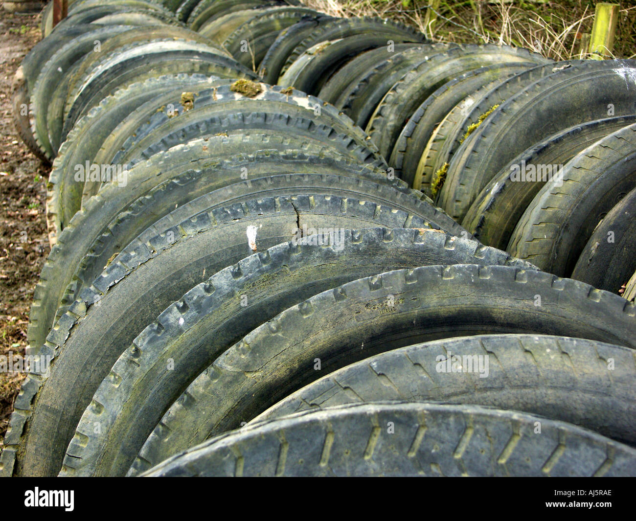 Old Tyres covered in mud and moss stacked in a field Stock Photo - Alamy