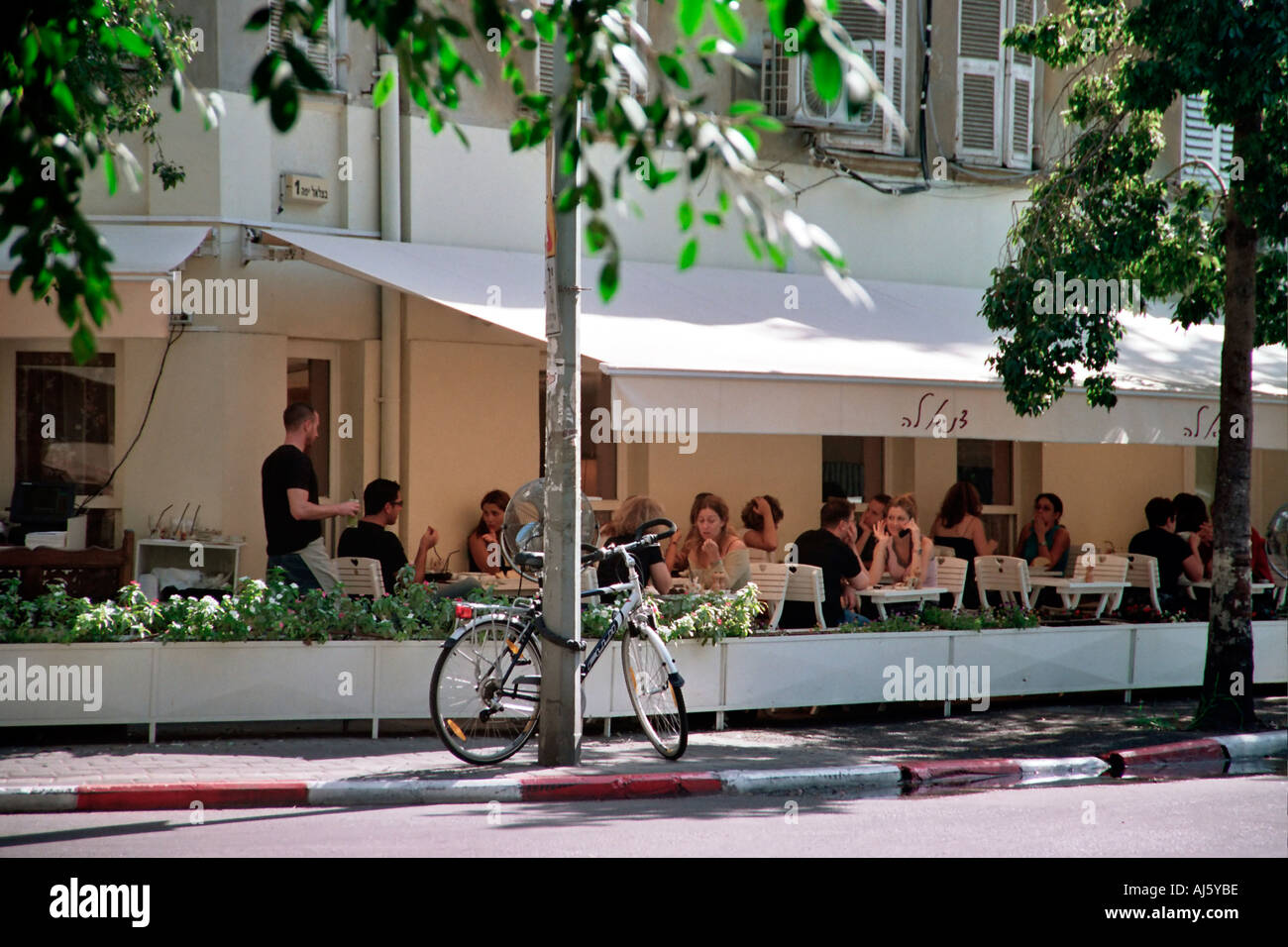A crowd of young people drinking coffee in an open air restaurant ...