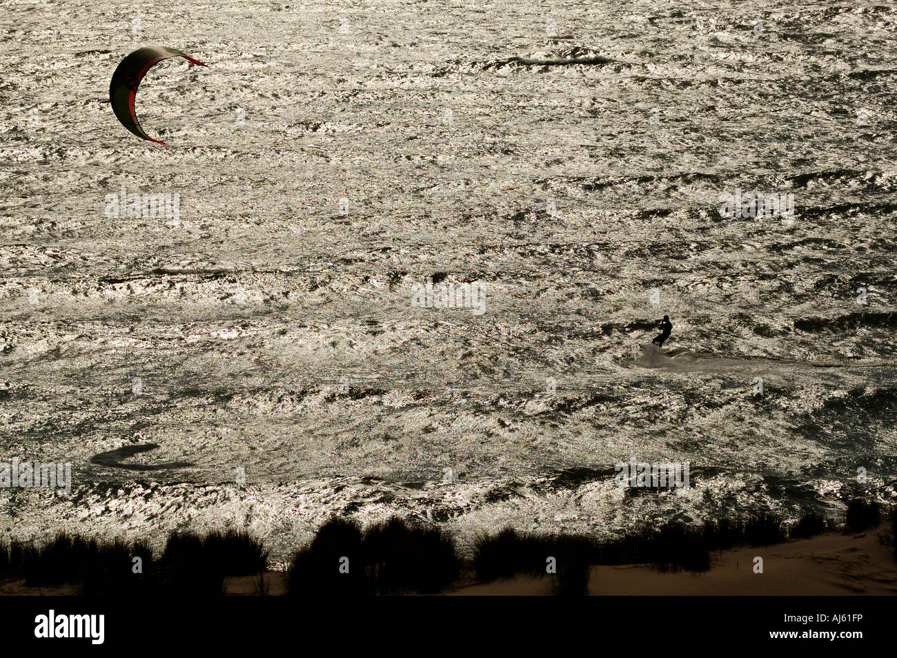 Kite men on a black and dark sea, shot with backlighting from a heli ...