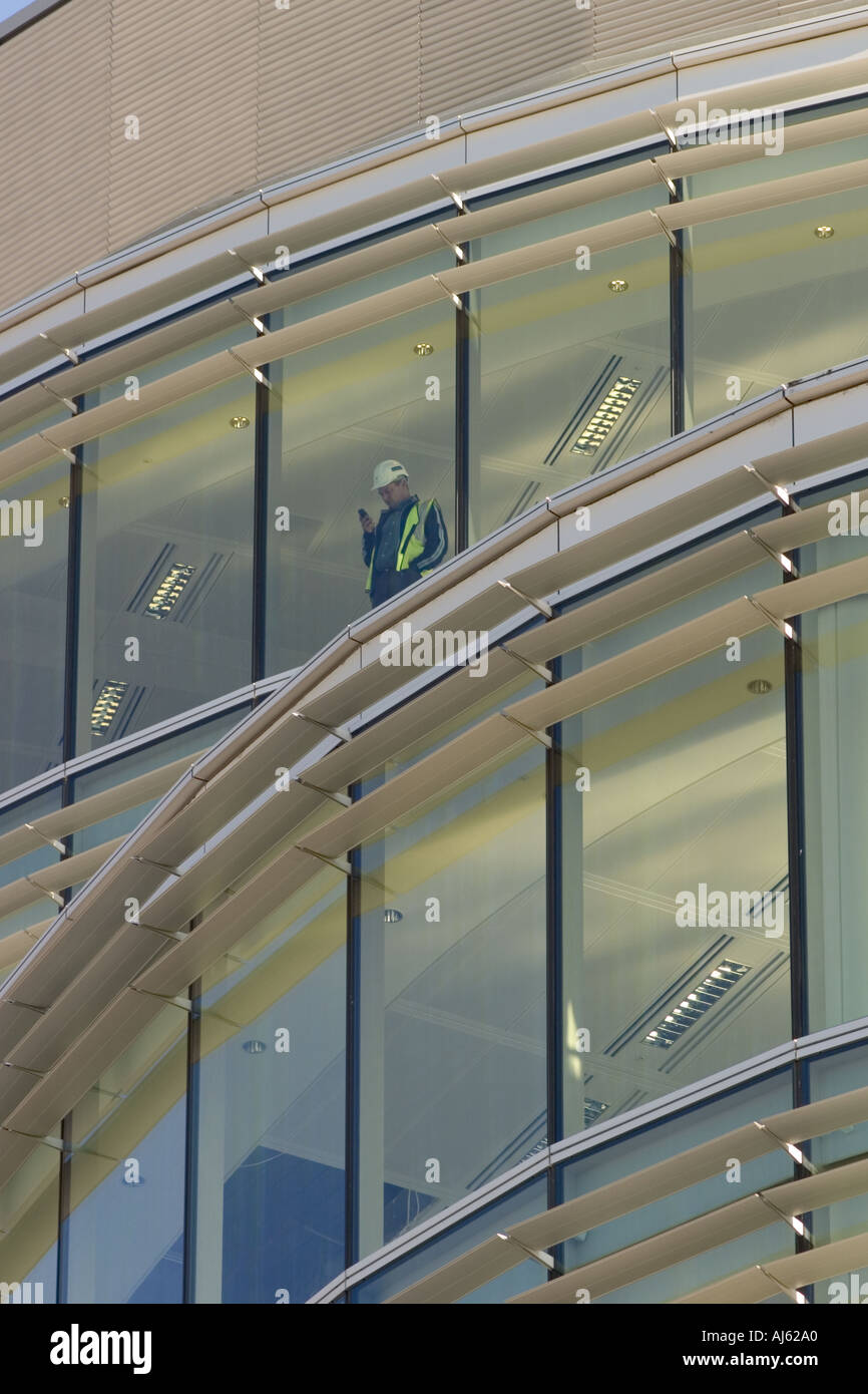 Construction foreman sending text message by window of empty office ...