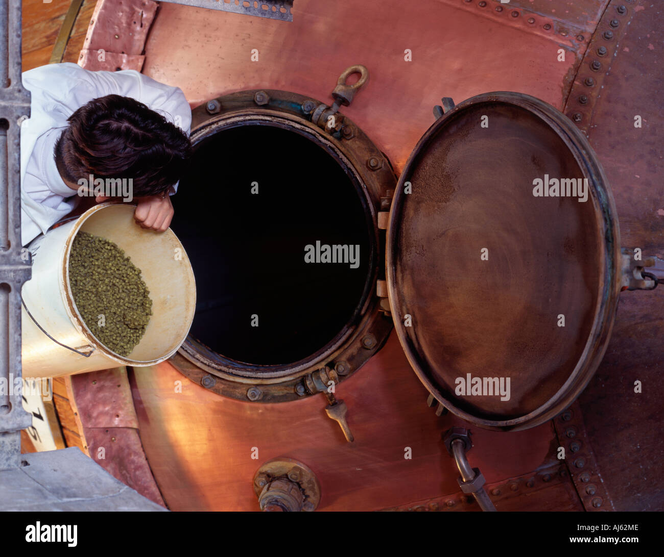 Tipping hop pellets into the brewing copper in brewery of George Gale ...