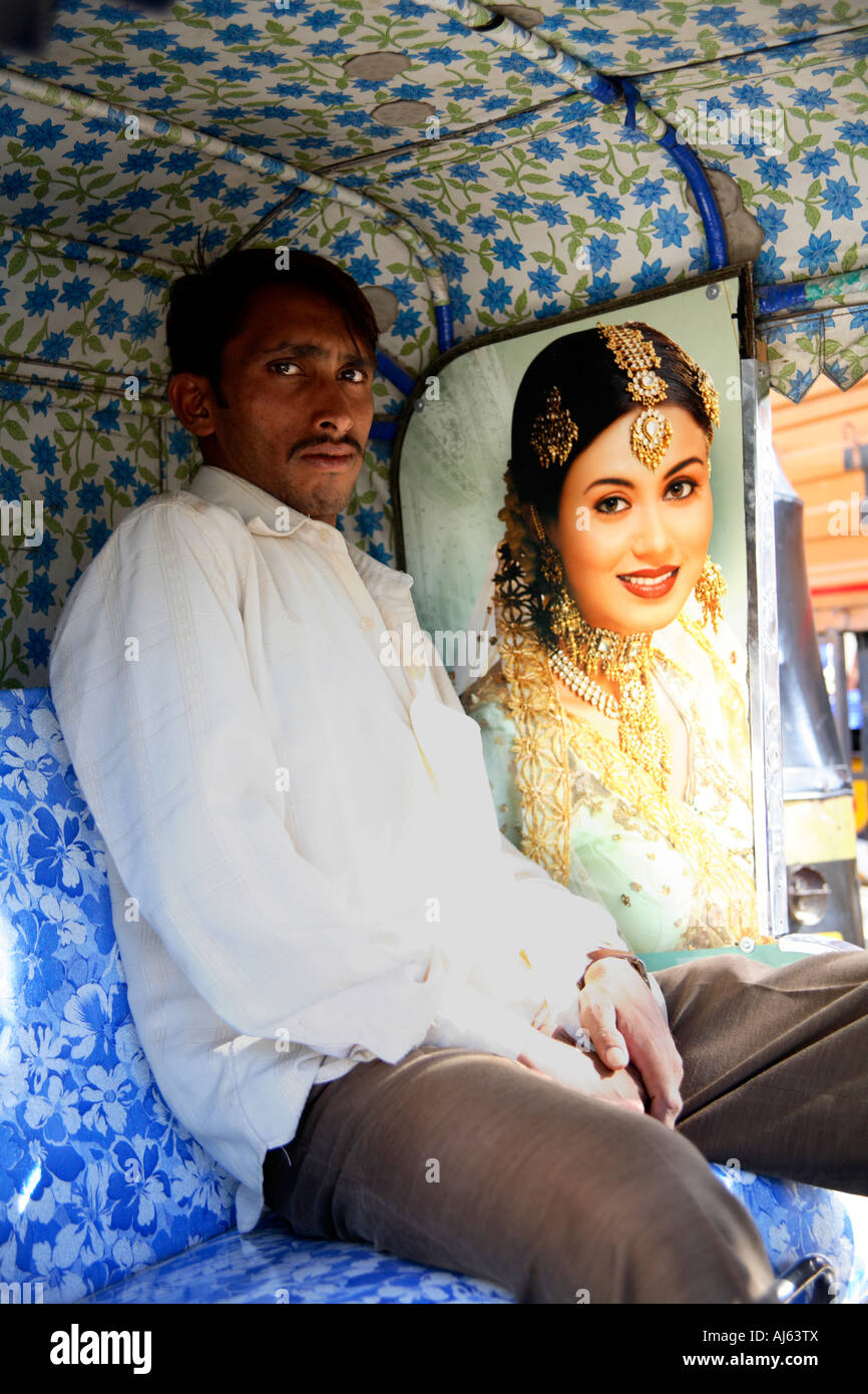 Indian Auto Rickshaw driver posing beside poster of elegant Indian ...
