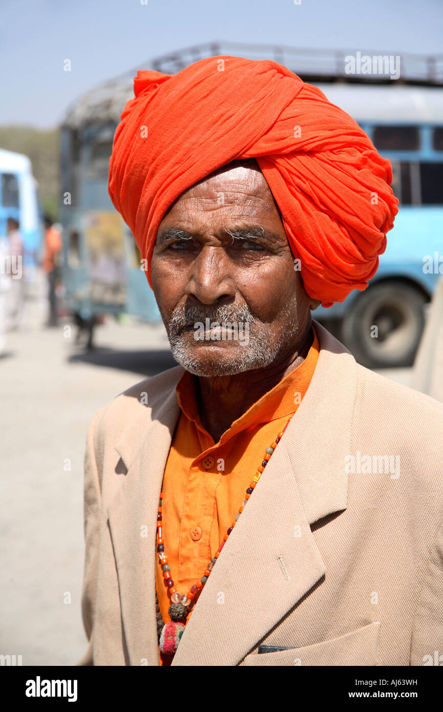Portrait of sorrowful Indian man at bus station wearing orange turban ...