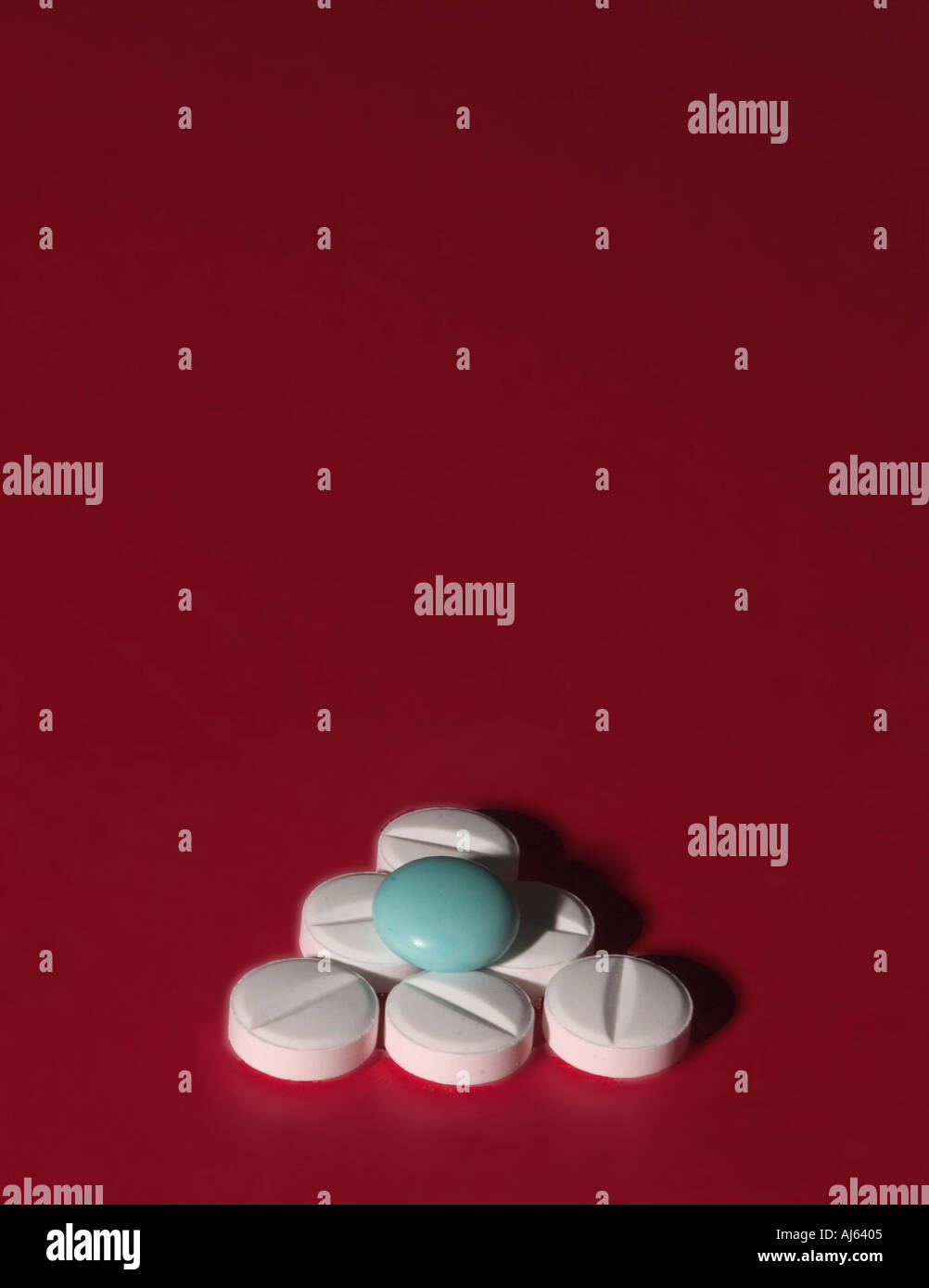 Triangle of white tablets with a single blue pill on top, symbolizing ...