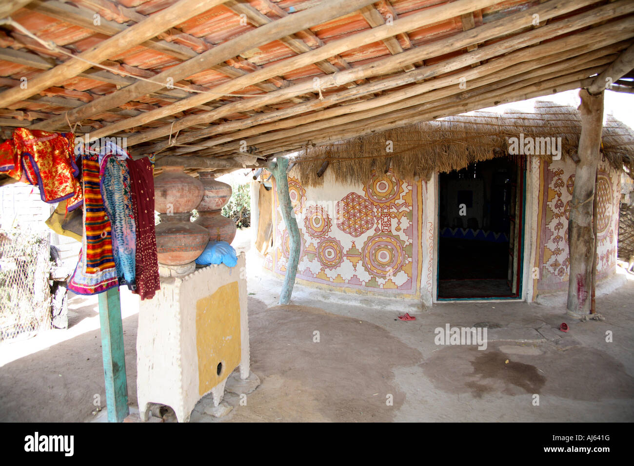 Patterned design on wall exterior of mud hut with thatched roof at home ...