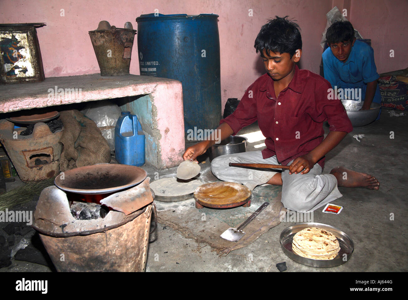 Young Indian boys cooking chapati in traditional archaic Indian kitchen ...
