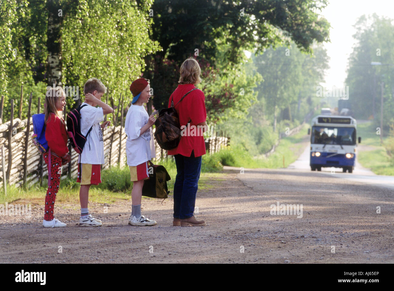 Children and parent waiting for school bus on country road in Sweden ...