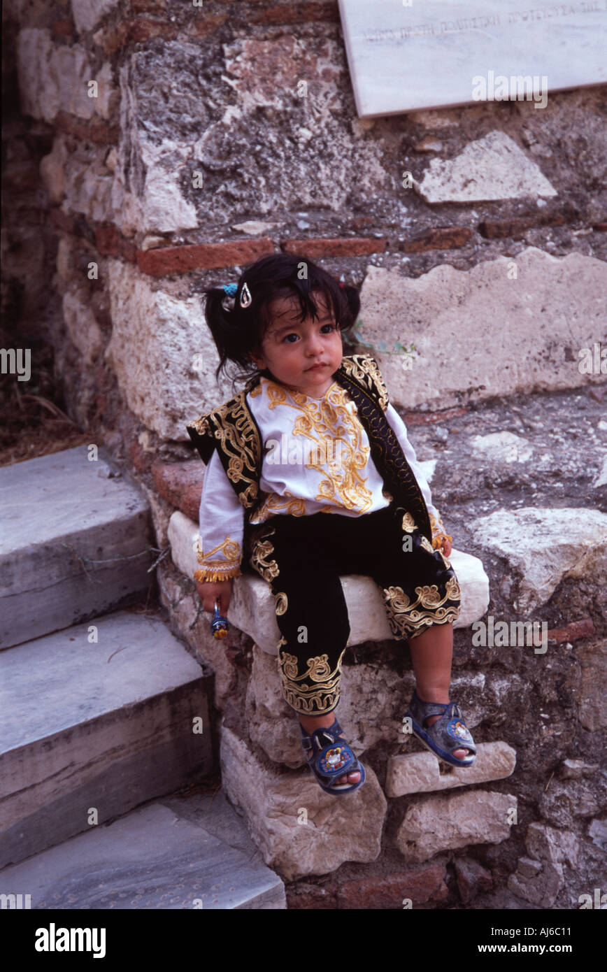 Little girl on traditional dress sitting on the steps to Acopolis ...