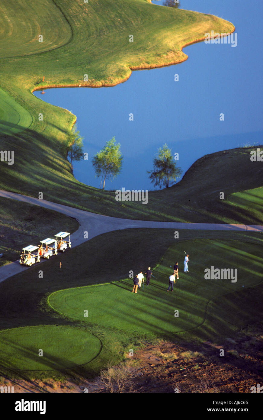 Aerial view of golf course near lake with golfers and three golf carts ...