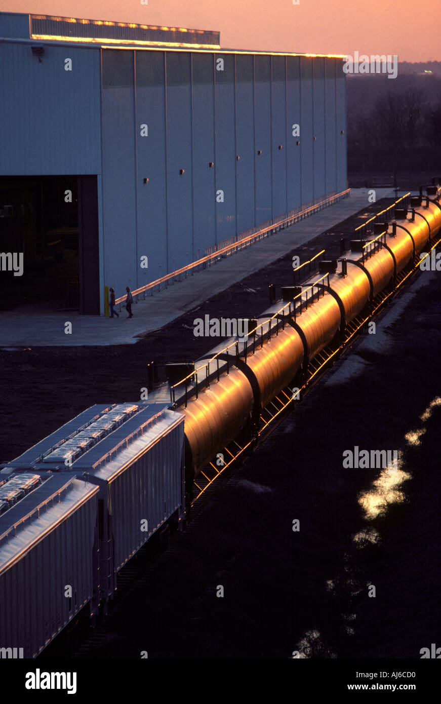 Railroad tank cars alongside large warehouse Stock Photo - Alamy