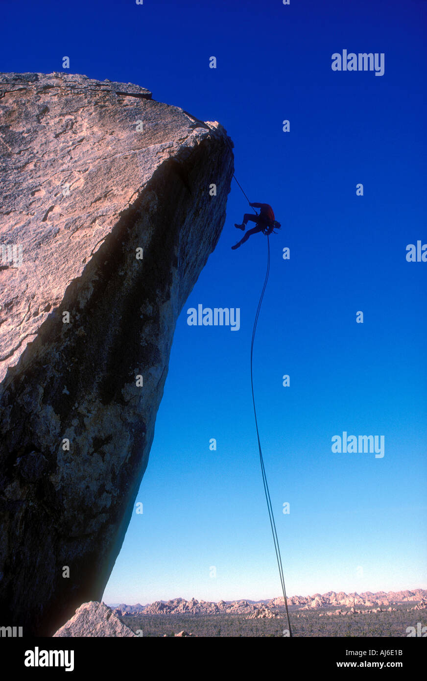 Rock climber rappeling off of large boulder in Joshua Tree National ...