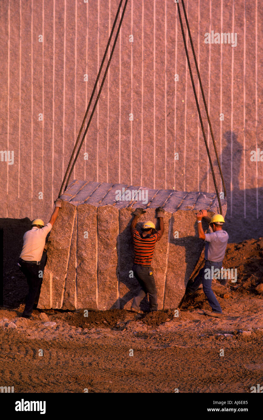 Three workers moving large block of granite or stone in quarry Stock ...