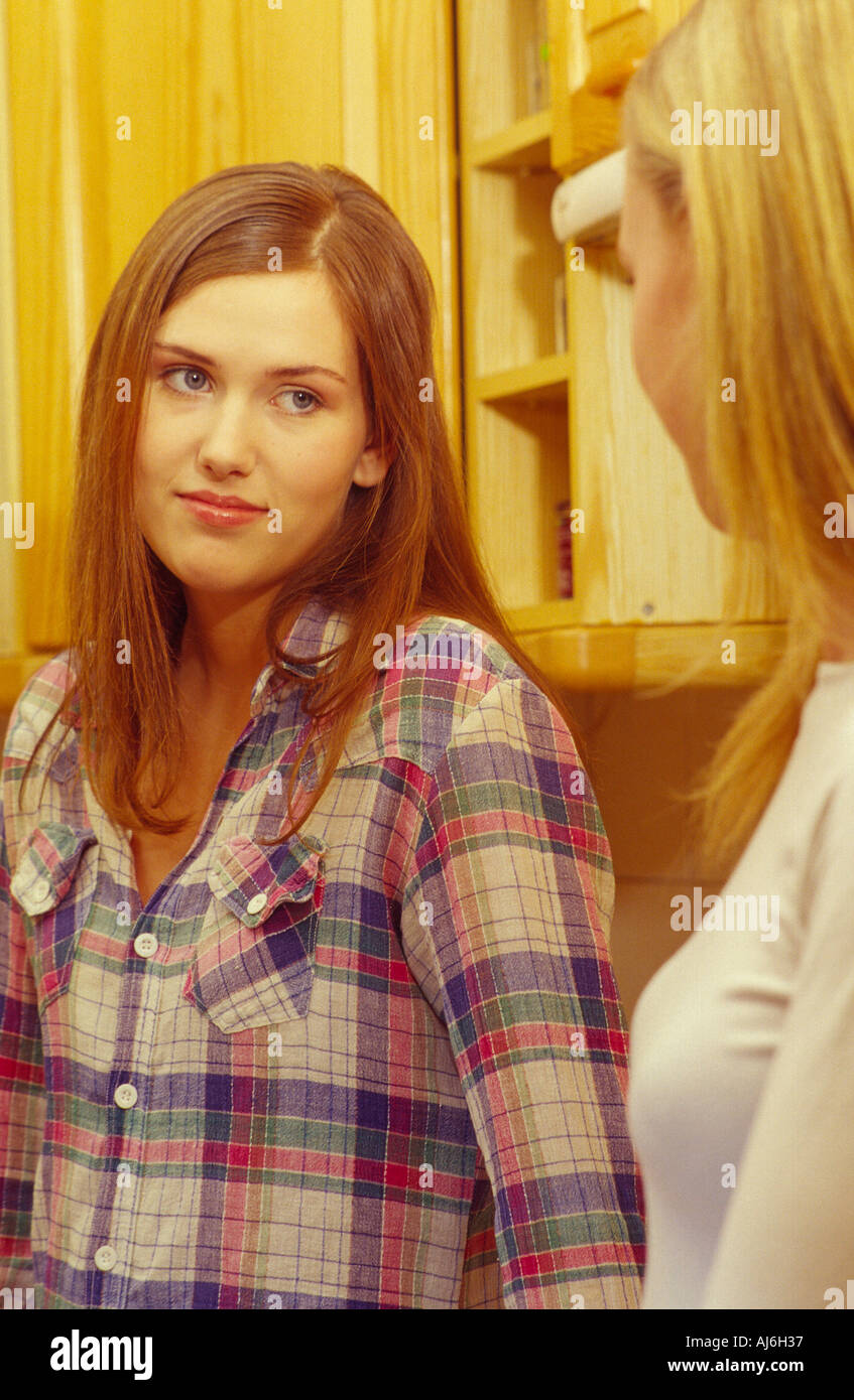 Two young women talking in the kitchen Stock Photo - Alamy