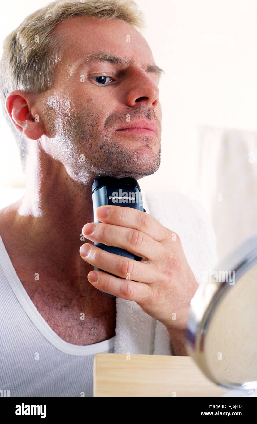 Young man shaving his beard in the mirror Stock Photo - Alamy