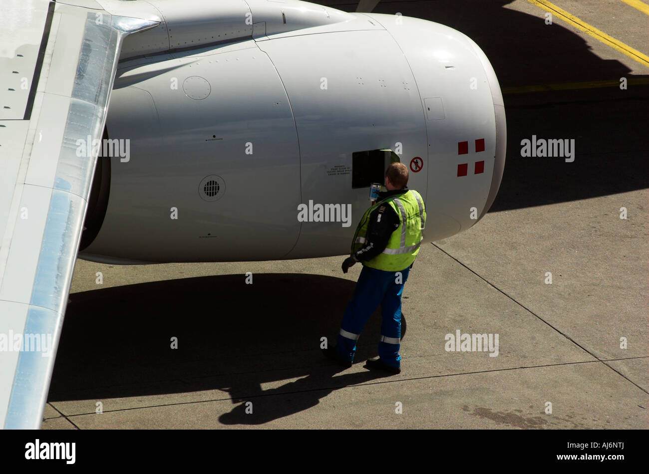 A ramp worker inspecting an engine on an aircraft at Amsterdam Schipol ...