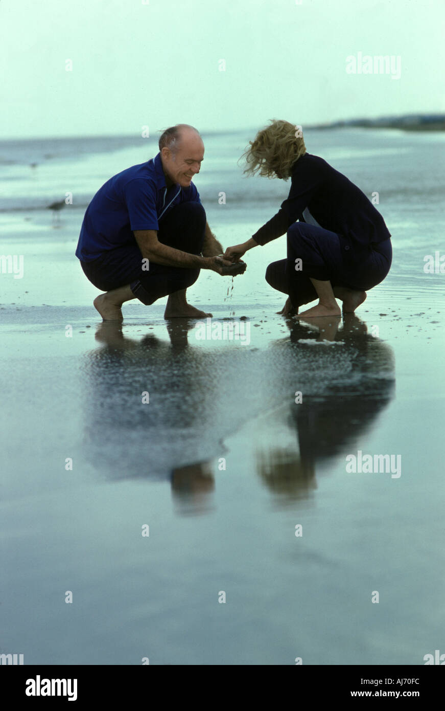 Senior couple looking for sea shells on Galveston Texas beach Stock ...