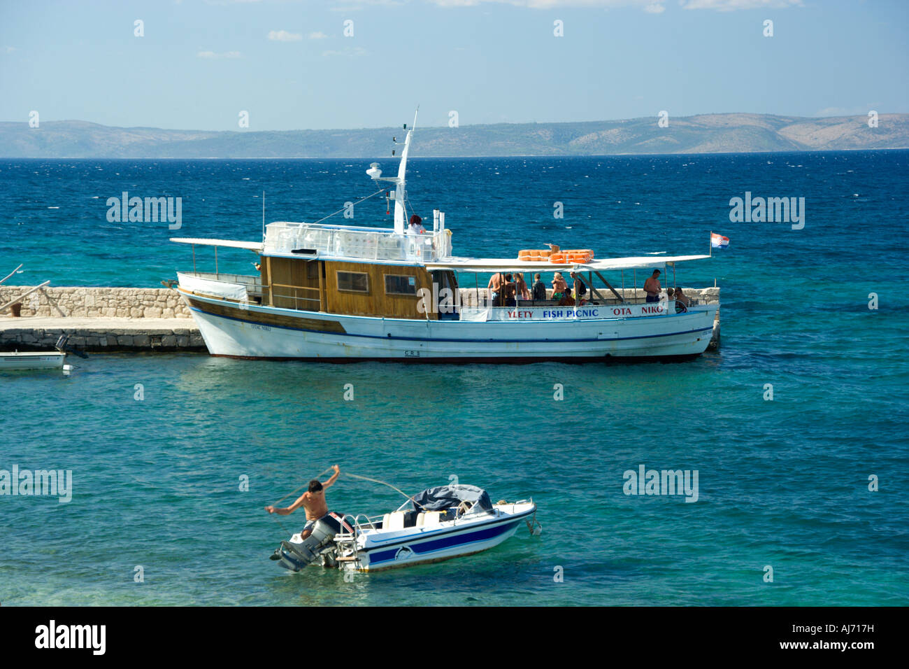 Cruise ship and fisherman in his boat in Duba Peljeska port Croatia ...